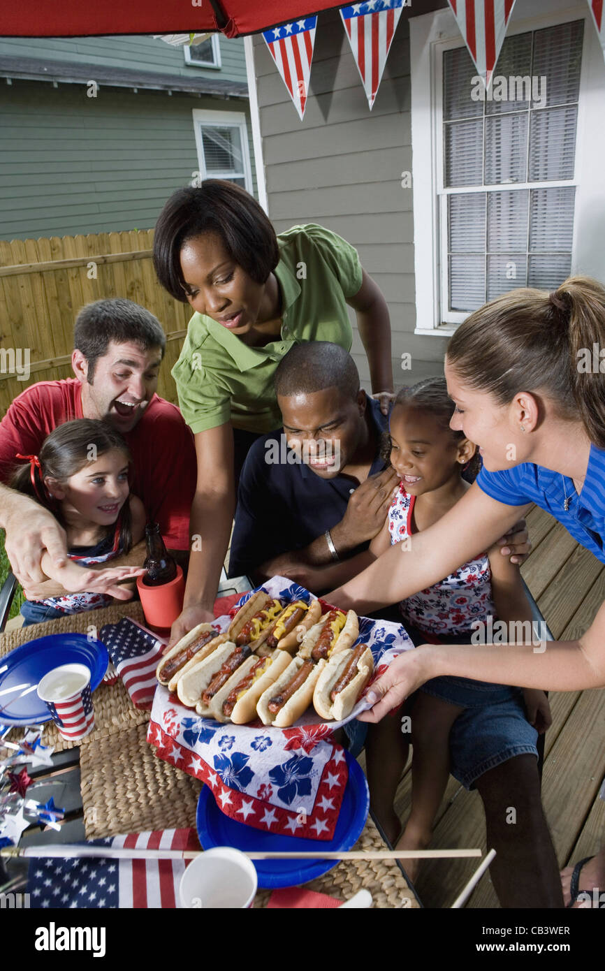 Two families on backyard patio enjoying a cookout on the 4th of July ...