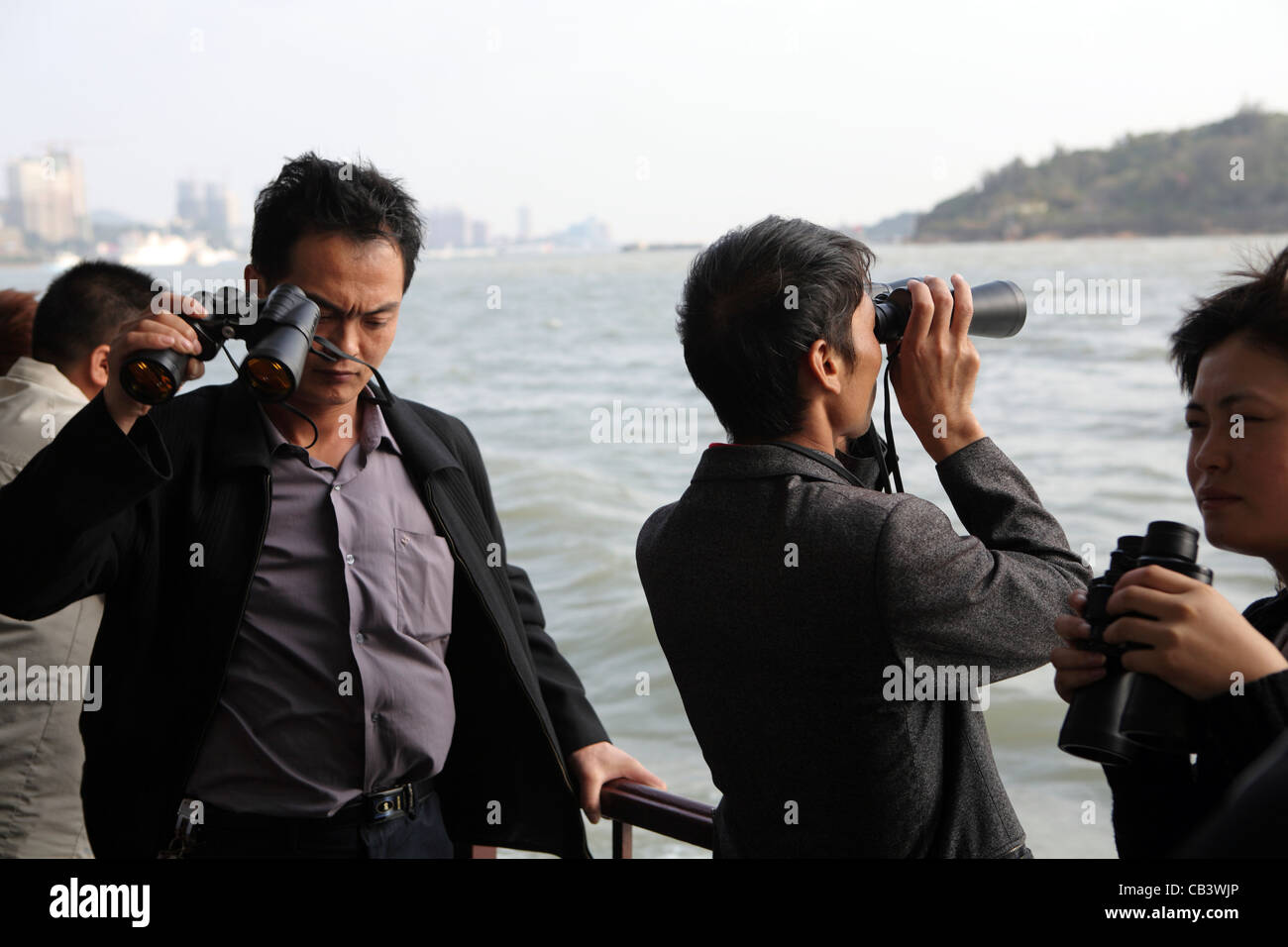 affluent middle class Chine professionals with binoculars on boat ferry ...