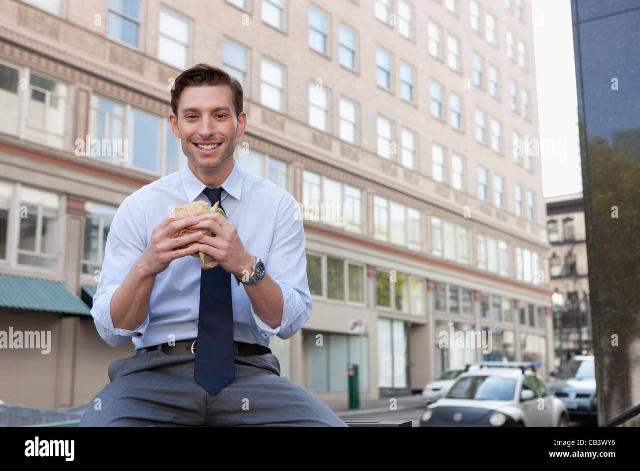 Businessman eating sandwich outside office building Stock Photo - Alamy