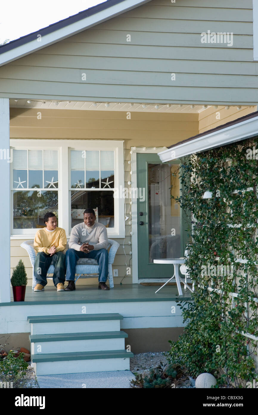 Father and son conversing while sitting on porch Stock Photo - Alamy