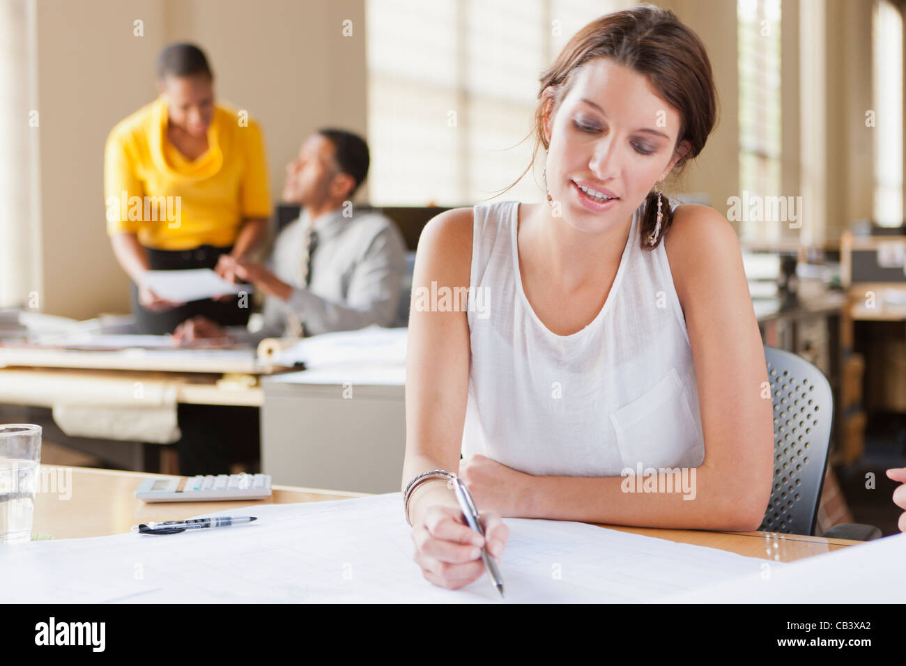 Woman at desk looking over plans Stock Photo - Alamy