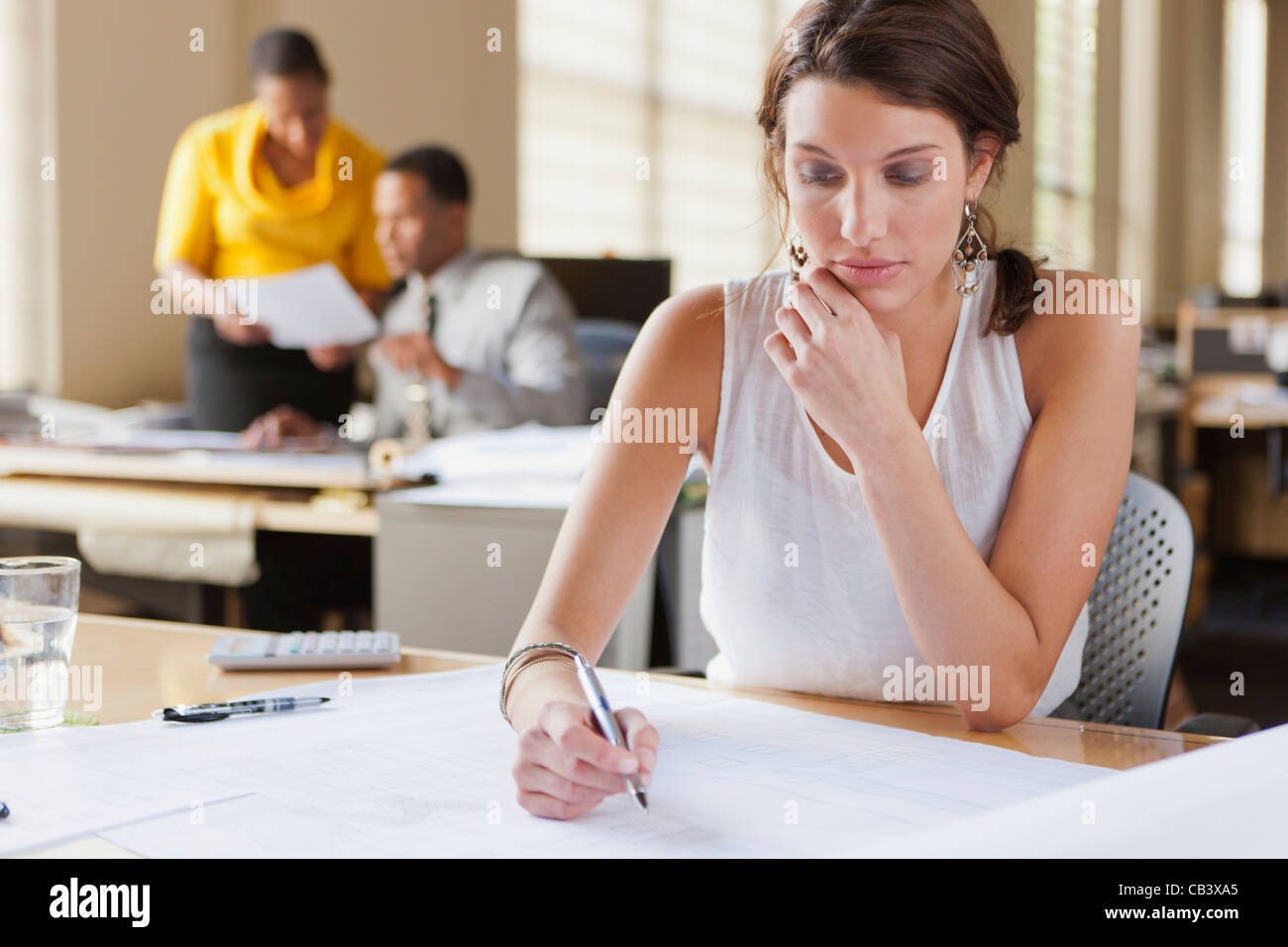 Woman at desk looking over plans Stock Photo - Alamy