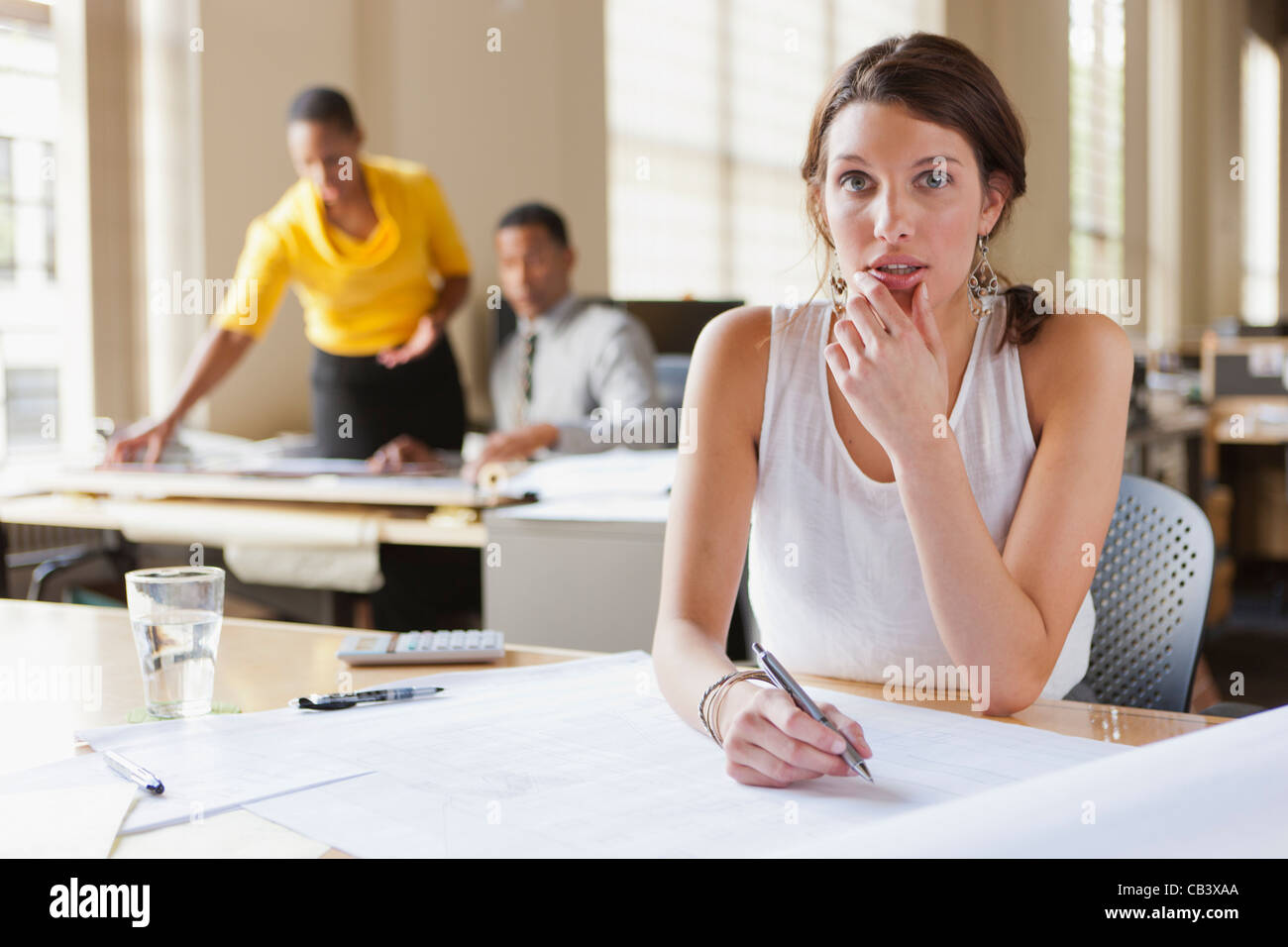 Woman at desk looking over plans Stock Photo - Alamy