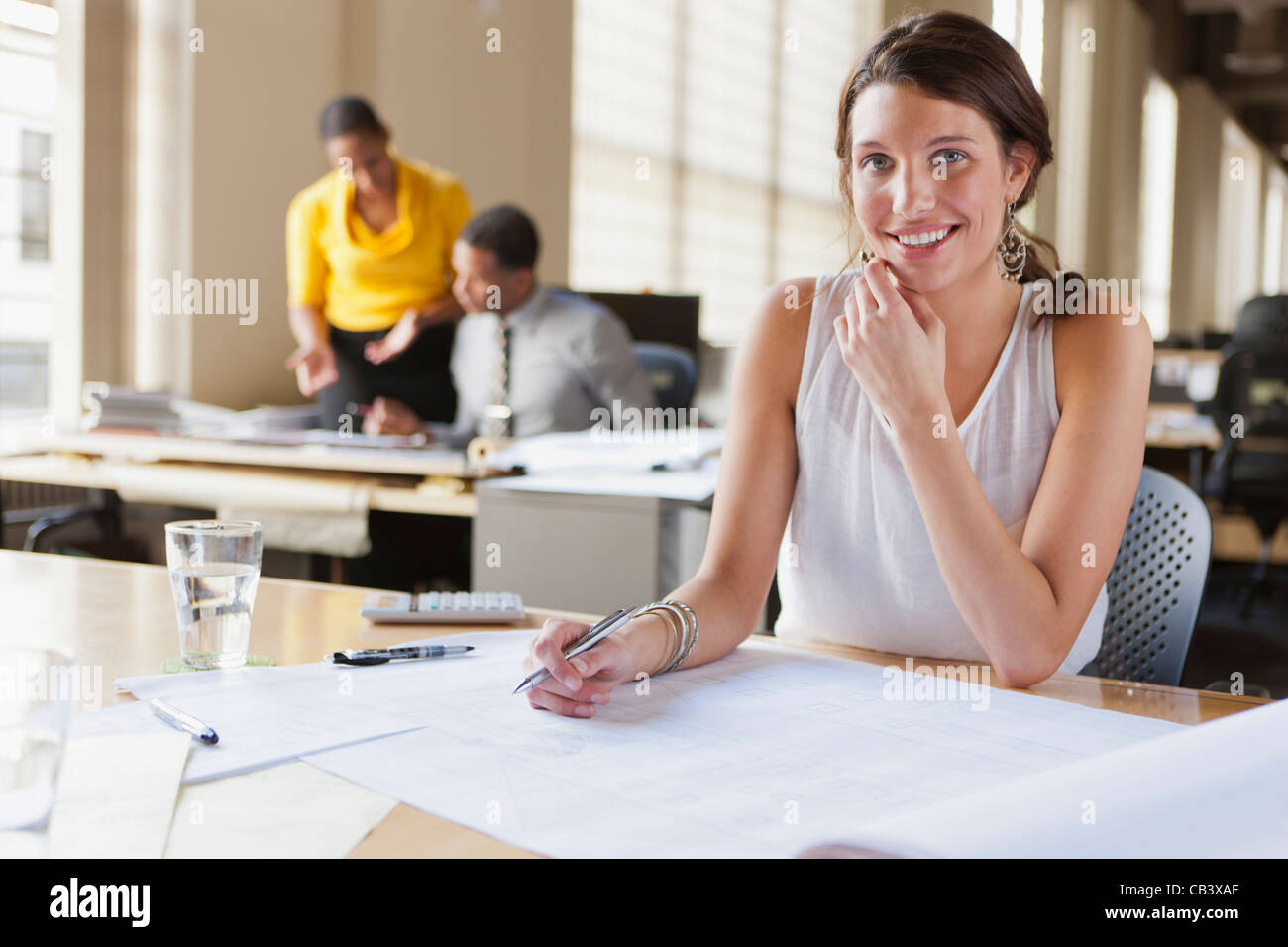 Woman at desk looking over plans, portrait Stock Photo - Alamy