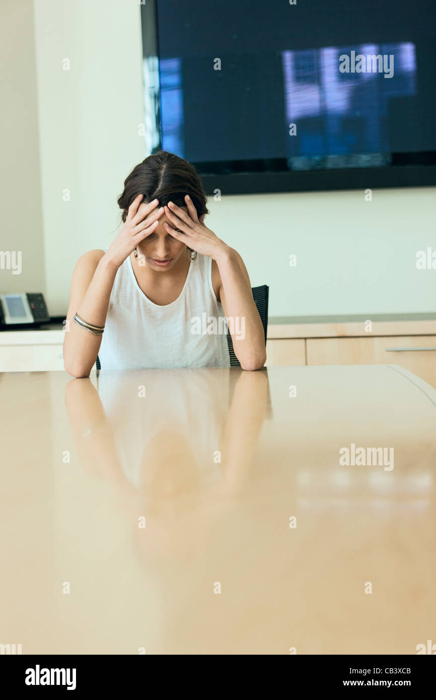 Woman sitting with head in hands at boardroom table Stock Photo - Alamy