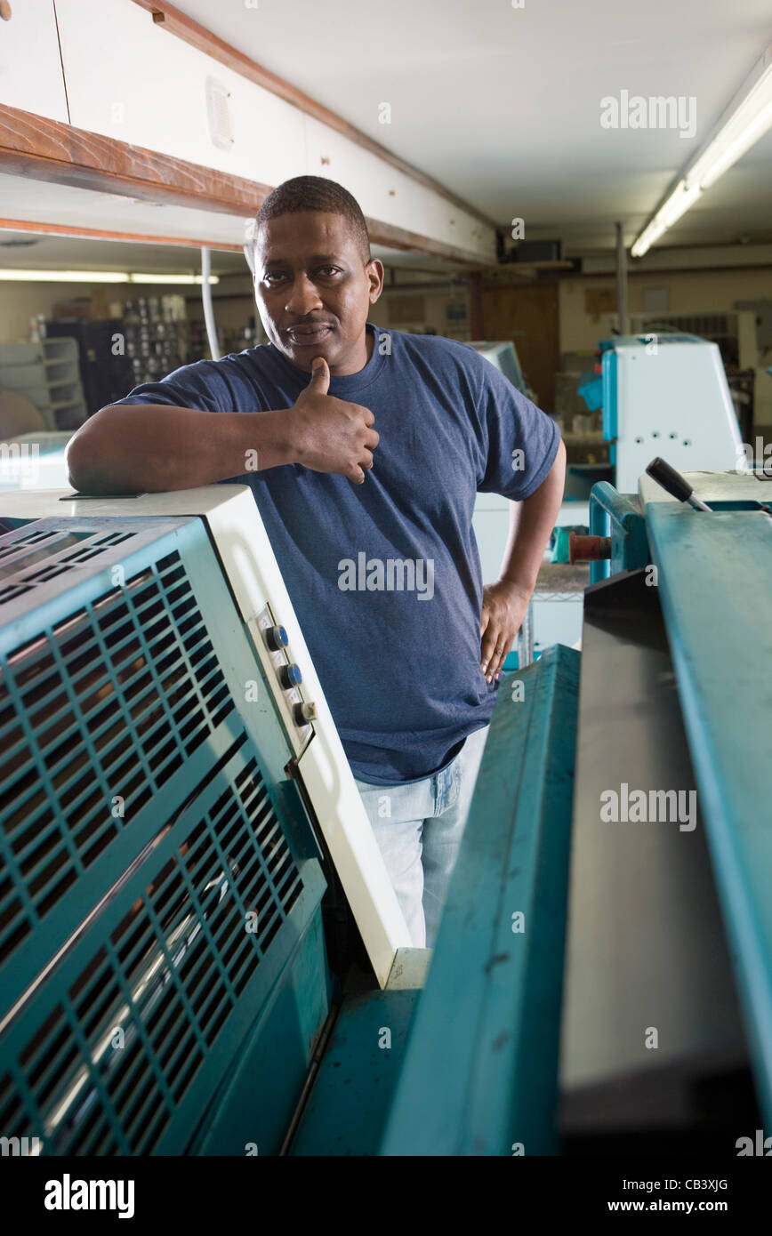 Portrait of a blue-collar man standing behind a printing machine Stock ...