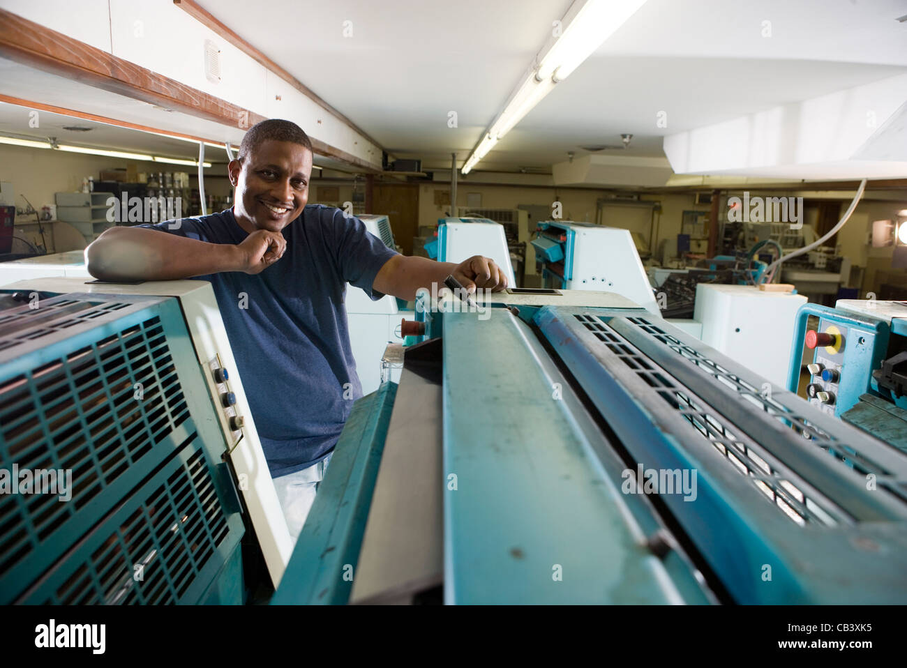 Portrait of a blue-collar man standing behind a printing machine Stock ...