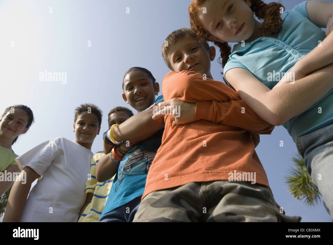 Low angle view of children with folded arms standing together at a ...