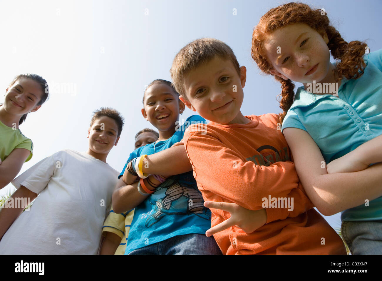 Low angle view of children with folded arms standing together at a ...
