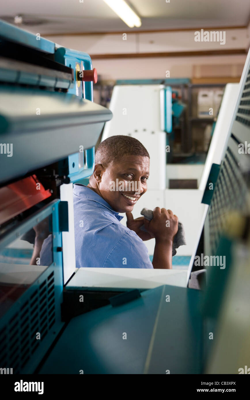Portrait of a man in coveralls sitting behind a printing machine Stock ...