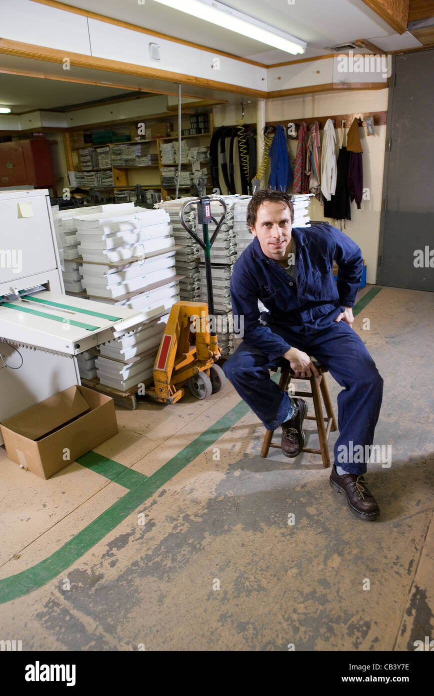 Portrait of a man sitting on a stool in a warehouse Stock Photo - Alamy
