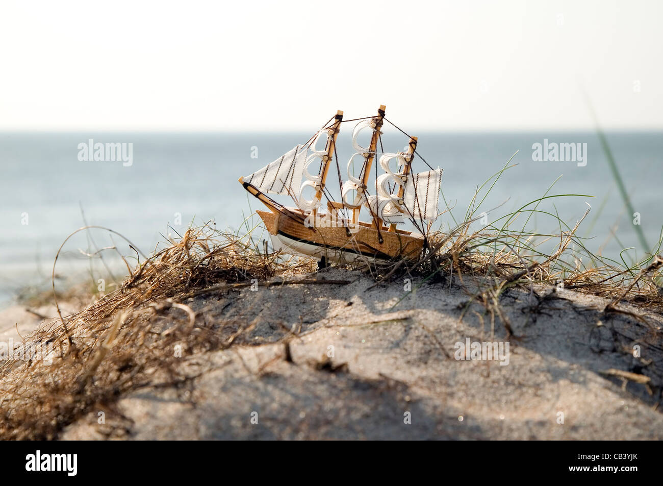 Miniature ship standing on sand, sea background Stock Photo - Alamy