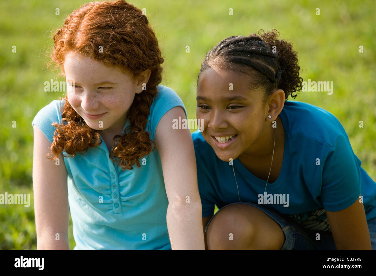 Two mischievous girls sitting together on the grass Stock Photo - Alamy