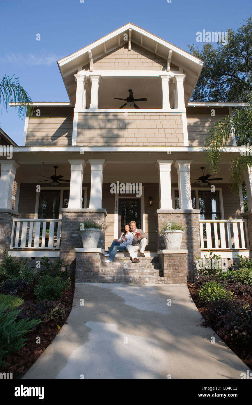 Interracial Couple Sitting On The Front Steps Of Their House Stock