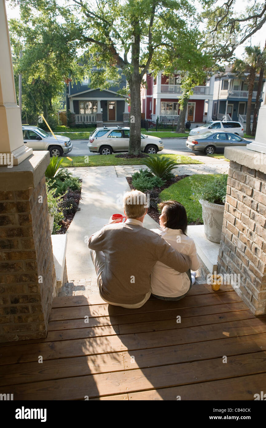 Interracial Couple Sitting On The Front Steps Of Their House Stock