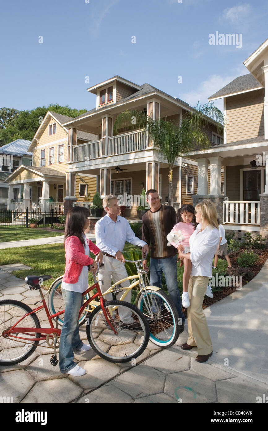 Family with young child conversing with neighbors in front of house ...