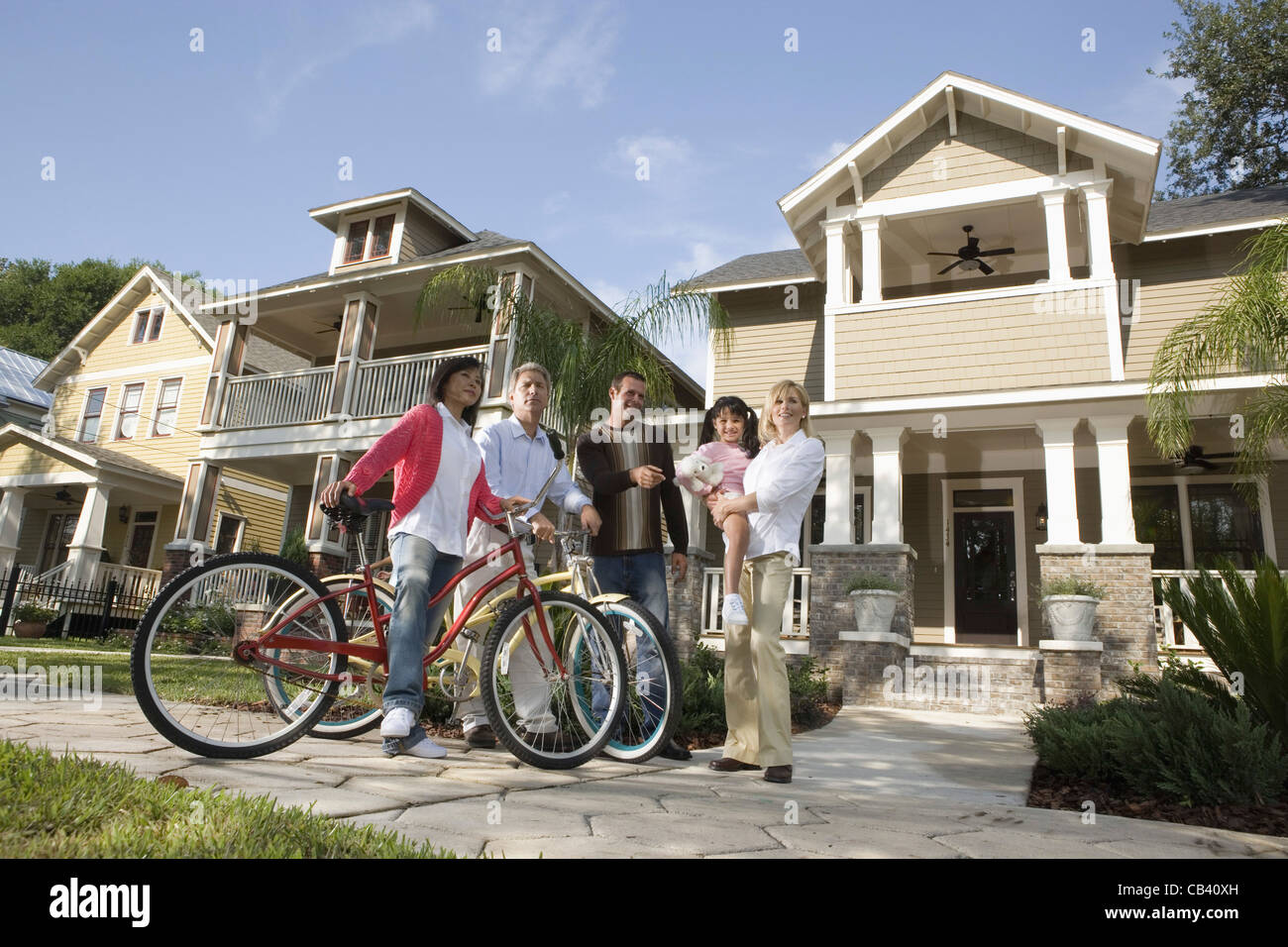 Family with young child conversing with neighbors in front of house ...