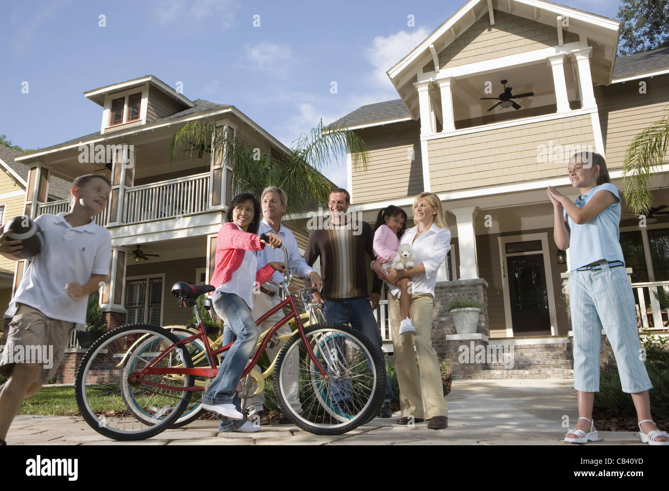 Family with young children conversing with neighbors in front of house ...