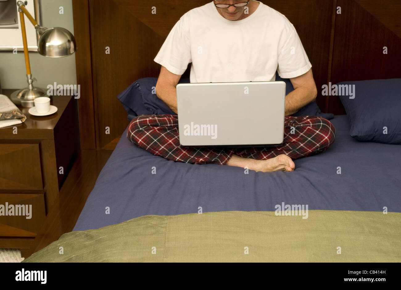 Telecommuter working from his bed via computer and wireless devices ...