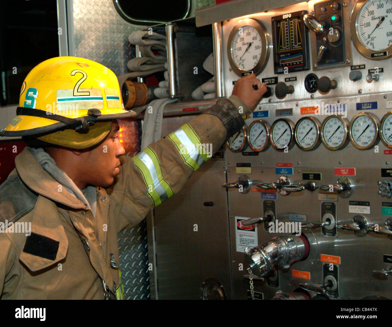 black firefighter studies the gages on the pump panel of a fire truck ...
