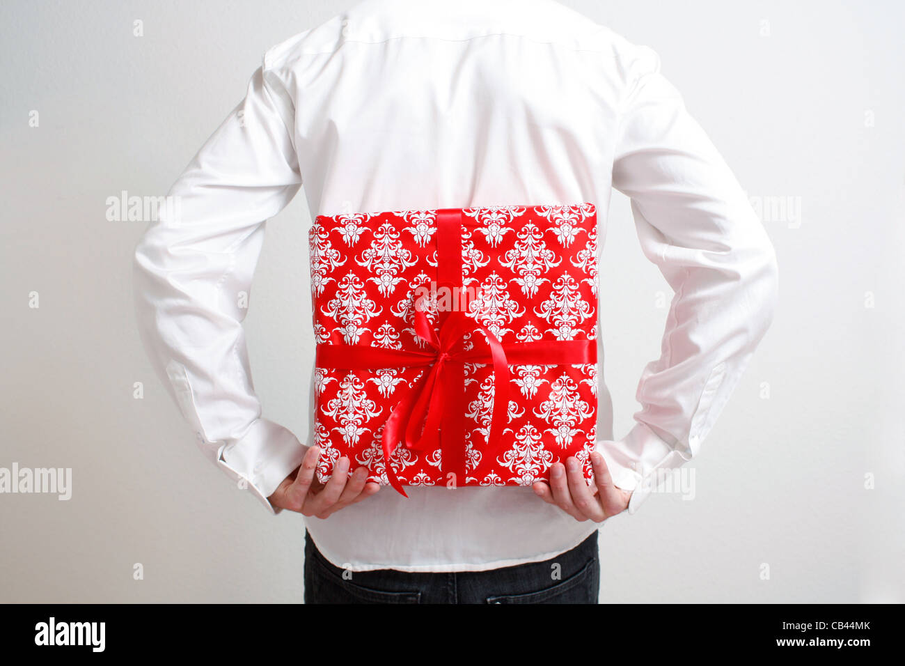 A man hiding a present behind his back Stock Photo - Alamy
