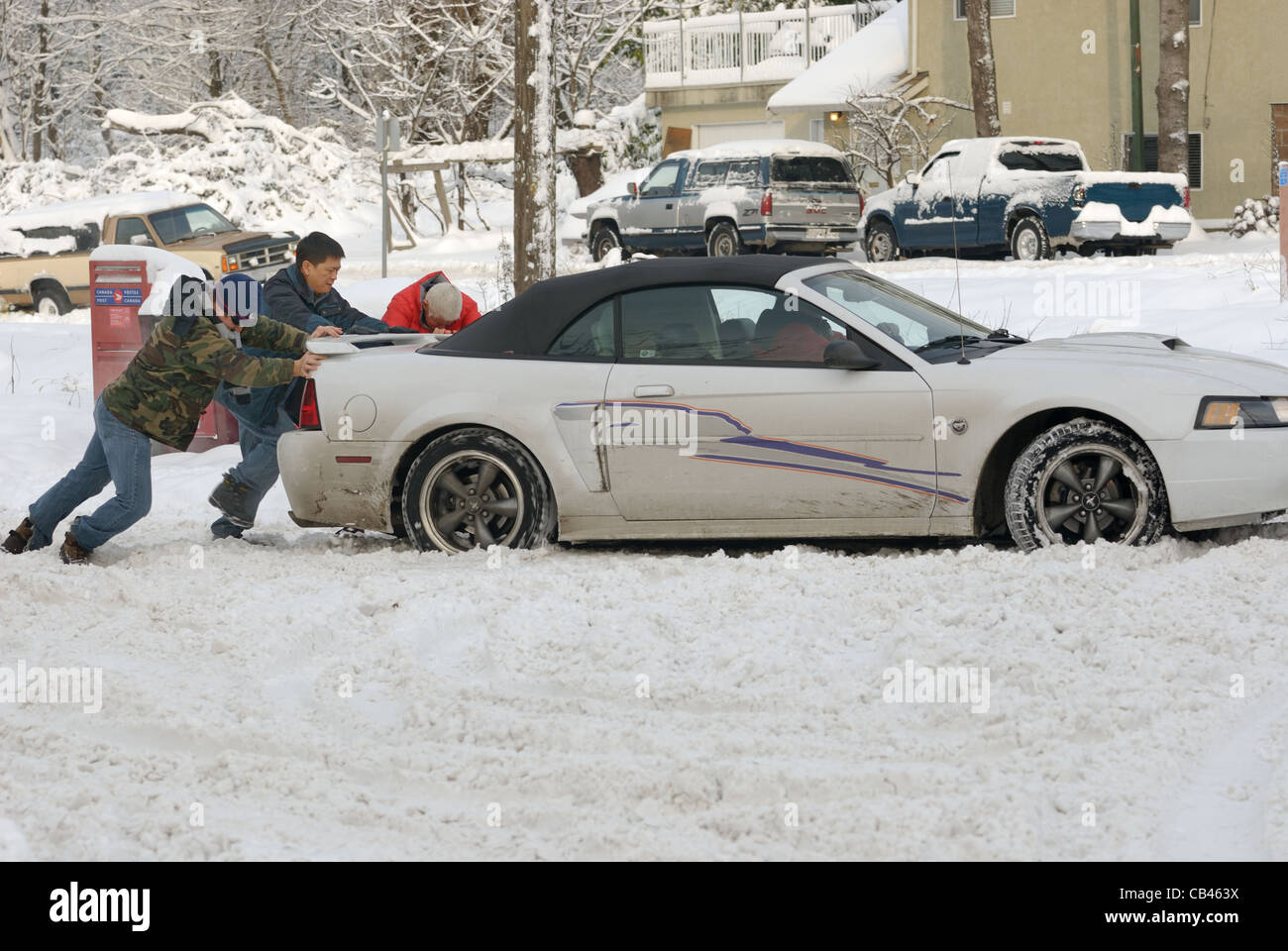Men pushing a mustang stuck in the snow Stock Photo - Alamy