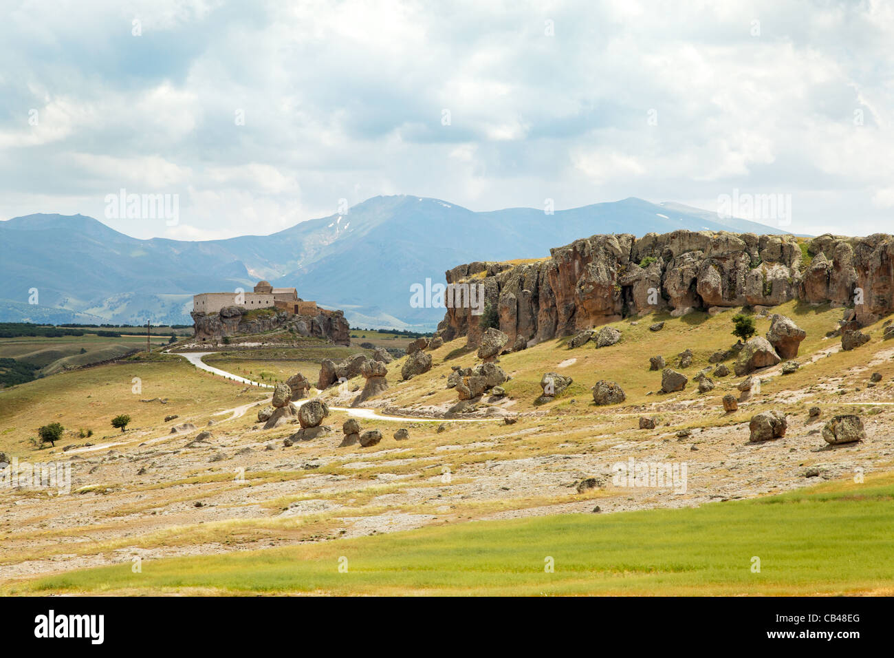 volcanic lava ash terrain with old church on a hill and mountain range ...