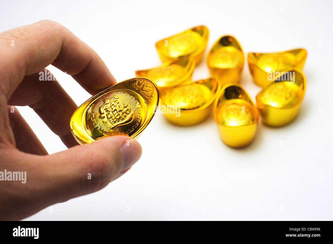 chinese gold ingots, a symbol of wealth for chinese. A hand is holidng ...