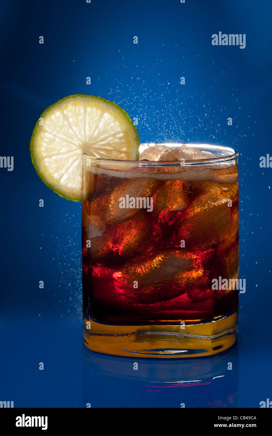 Cold cola with lemon and ice on blue background Stock Photo - Alamy