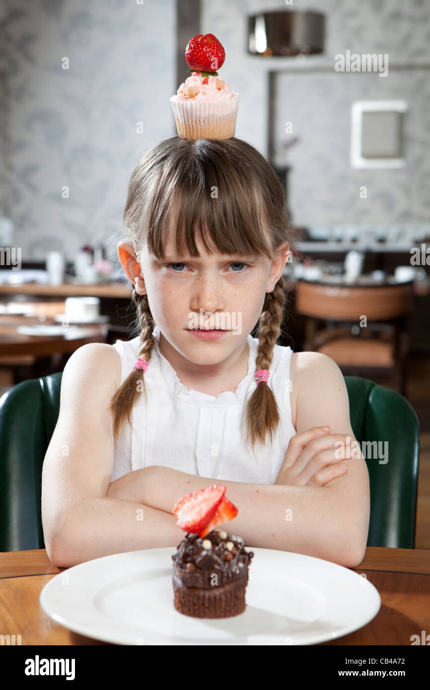 Grumpy girl with cupcake on head in posh high tea hotel Stock Photo - Alamy