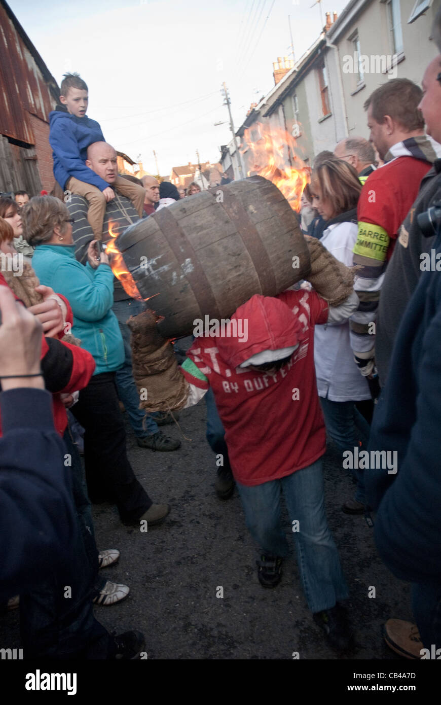 A young barrel roller runs through the crowd with a burning barrel at ...