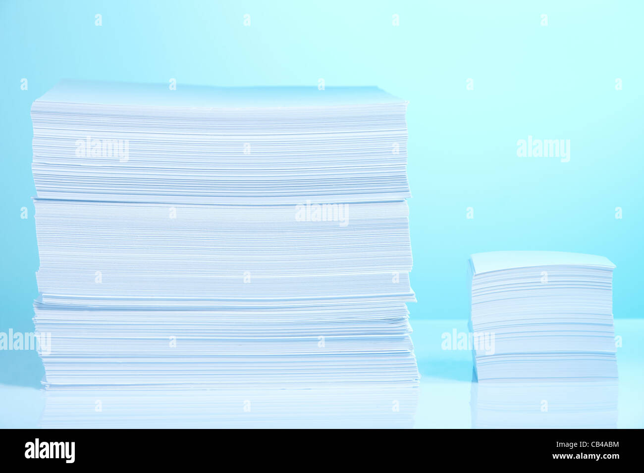 Big and small paper piles on blue background Stock Photo - Alamy