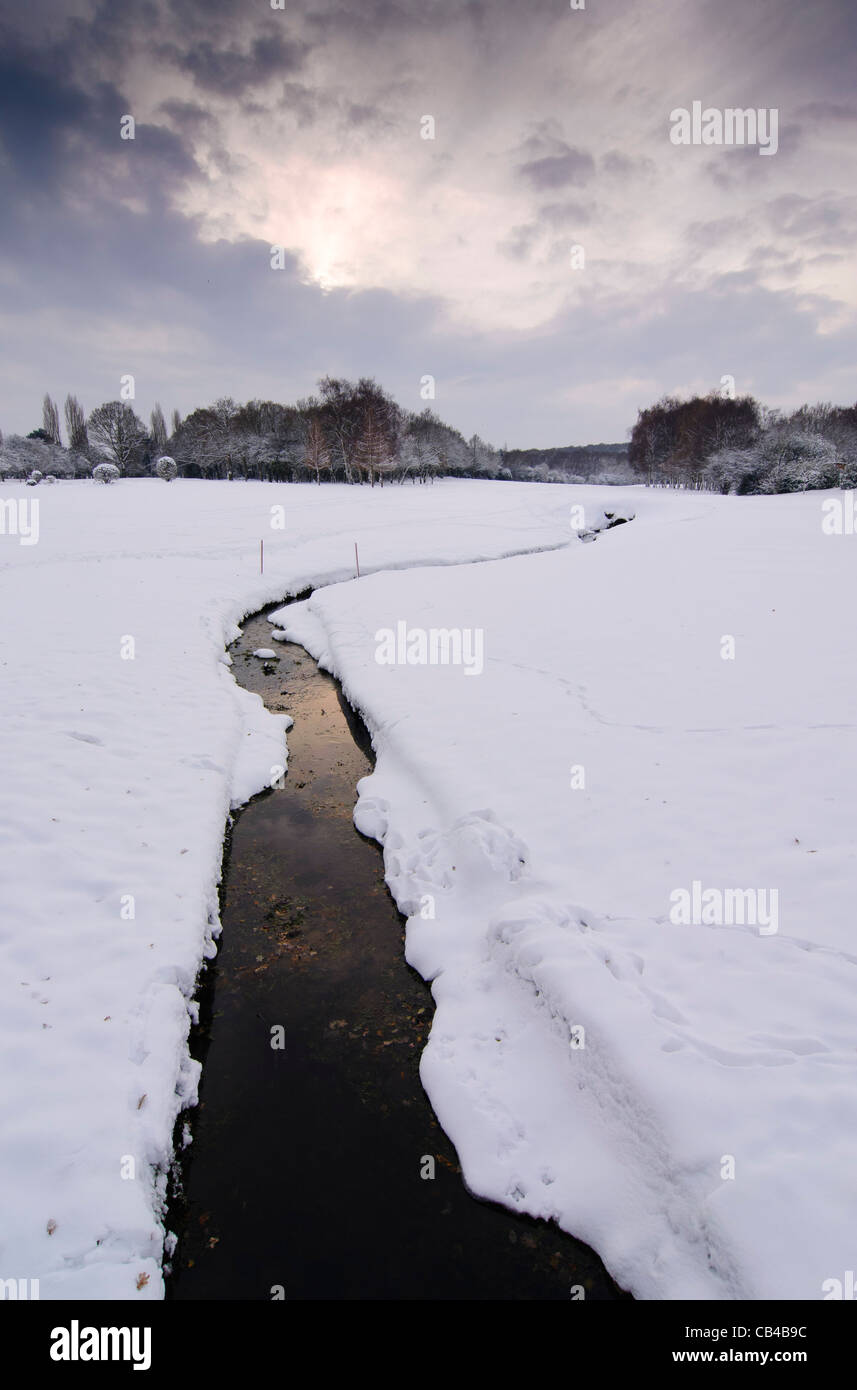 A stream meanders its way across a snow covered golf course under a ...
