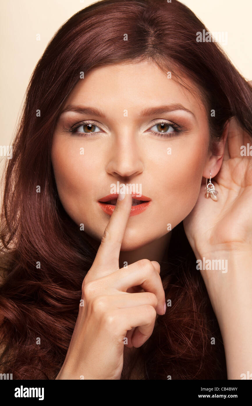 Beauty shoot Calm and listening woman showing shhh gesture and holding ...