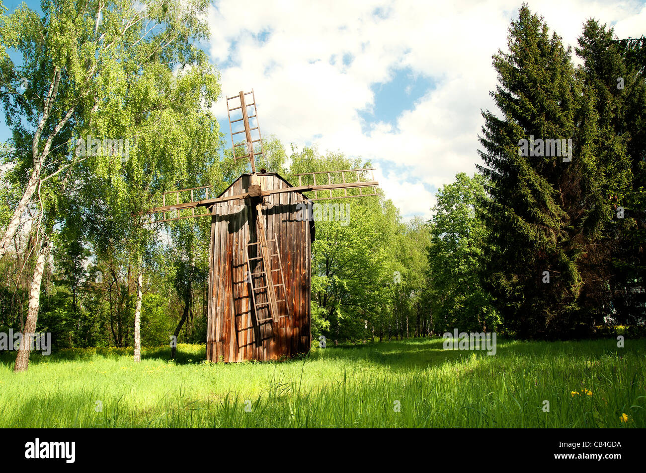 Old wooden windmill in the background of the summer forest Stock Photo ...