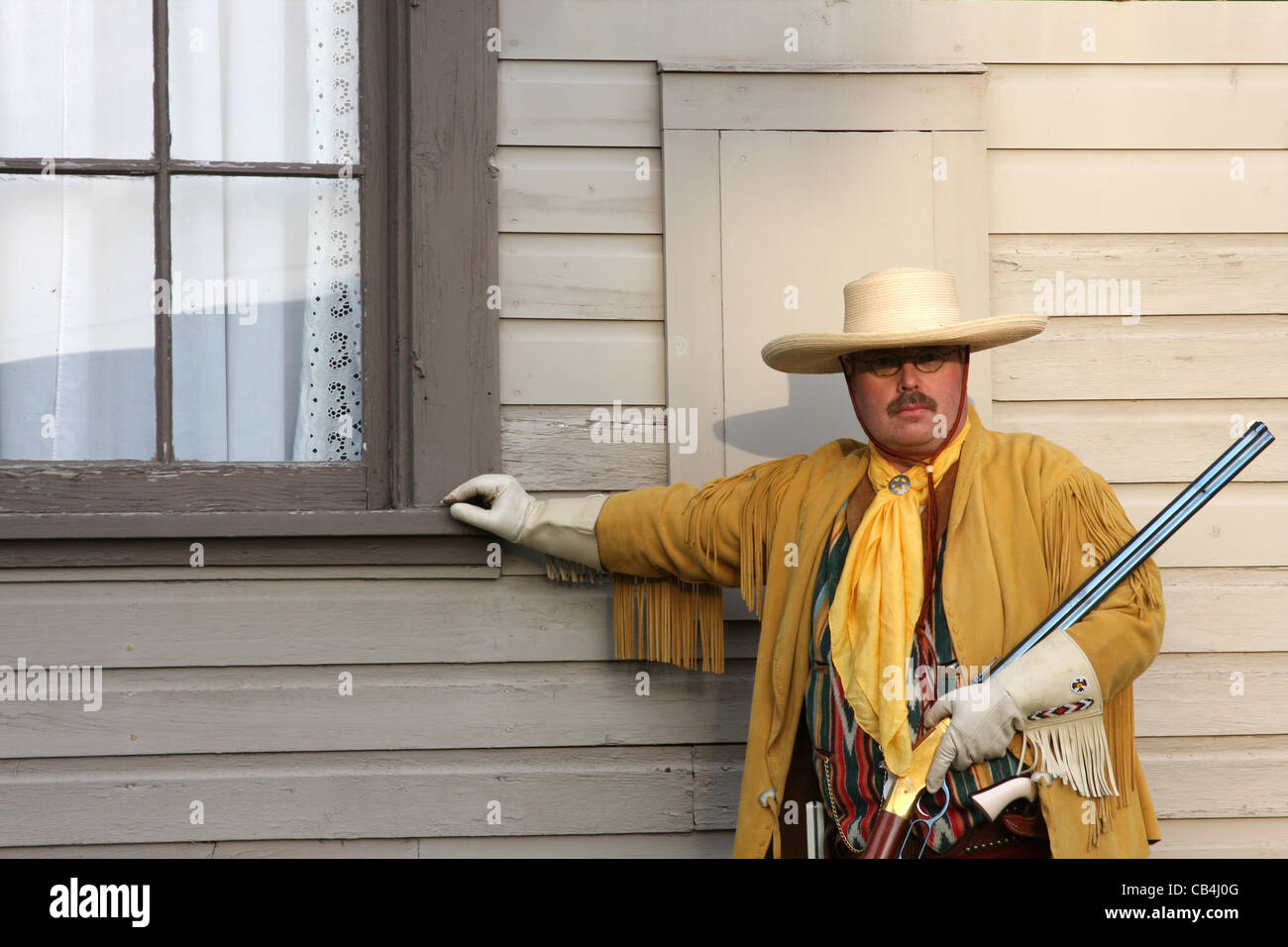 A southwestern cowboy standing in front of an old train depot window ...