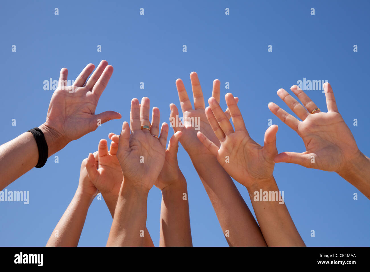 many hands raised to the blue sky (some motion blur Stock Photo - Alamy