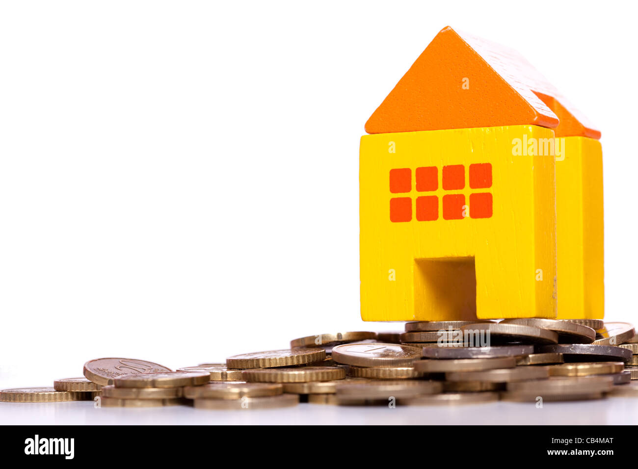 yellow toy house over a lot of golden coins (isolated on white Stock ...