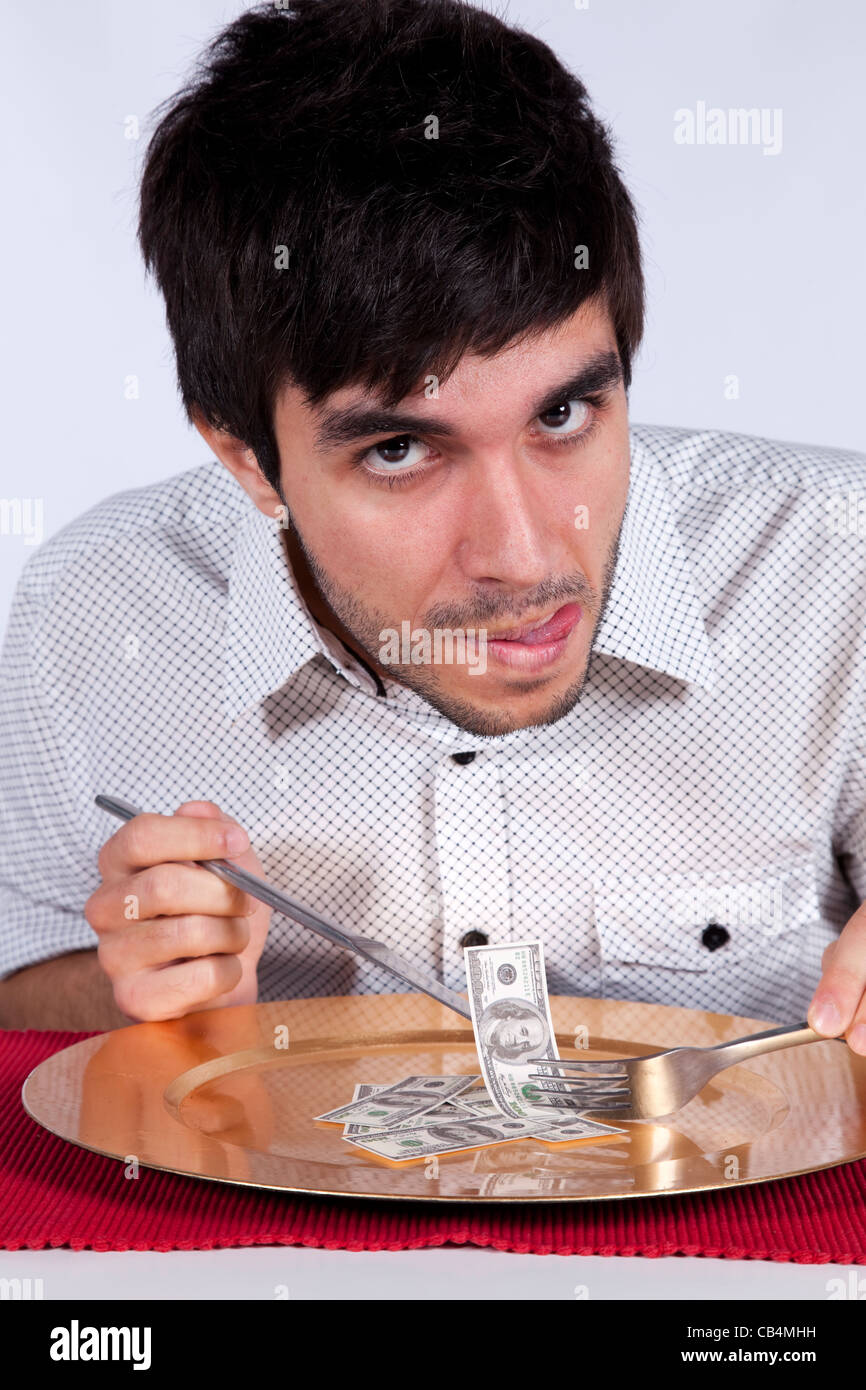 Man eating money at a plate with a fork and a knife Stock Photo - Alamy