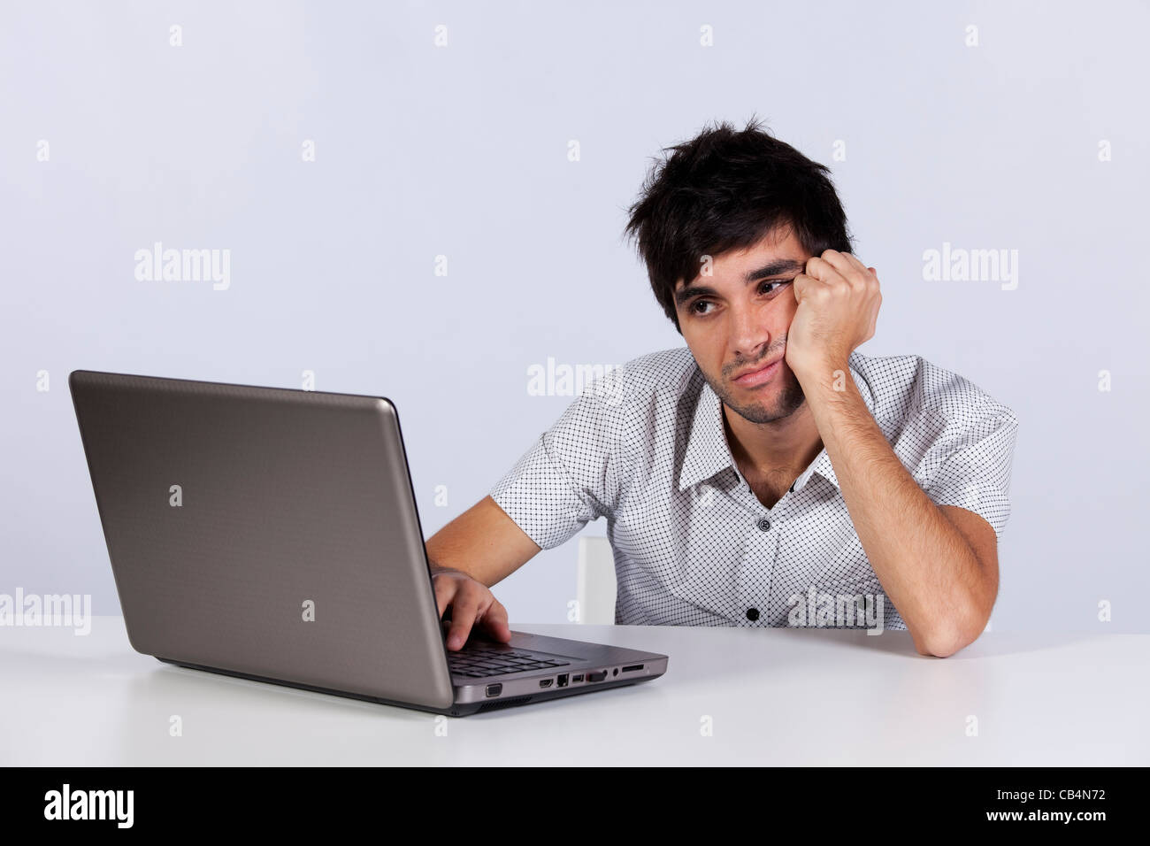 Young men working with his laptop with a bored face Stock Photo - Alamy