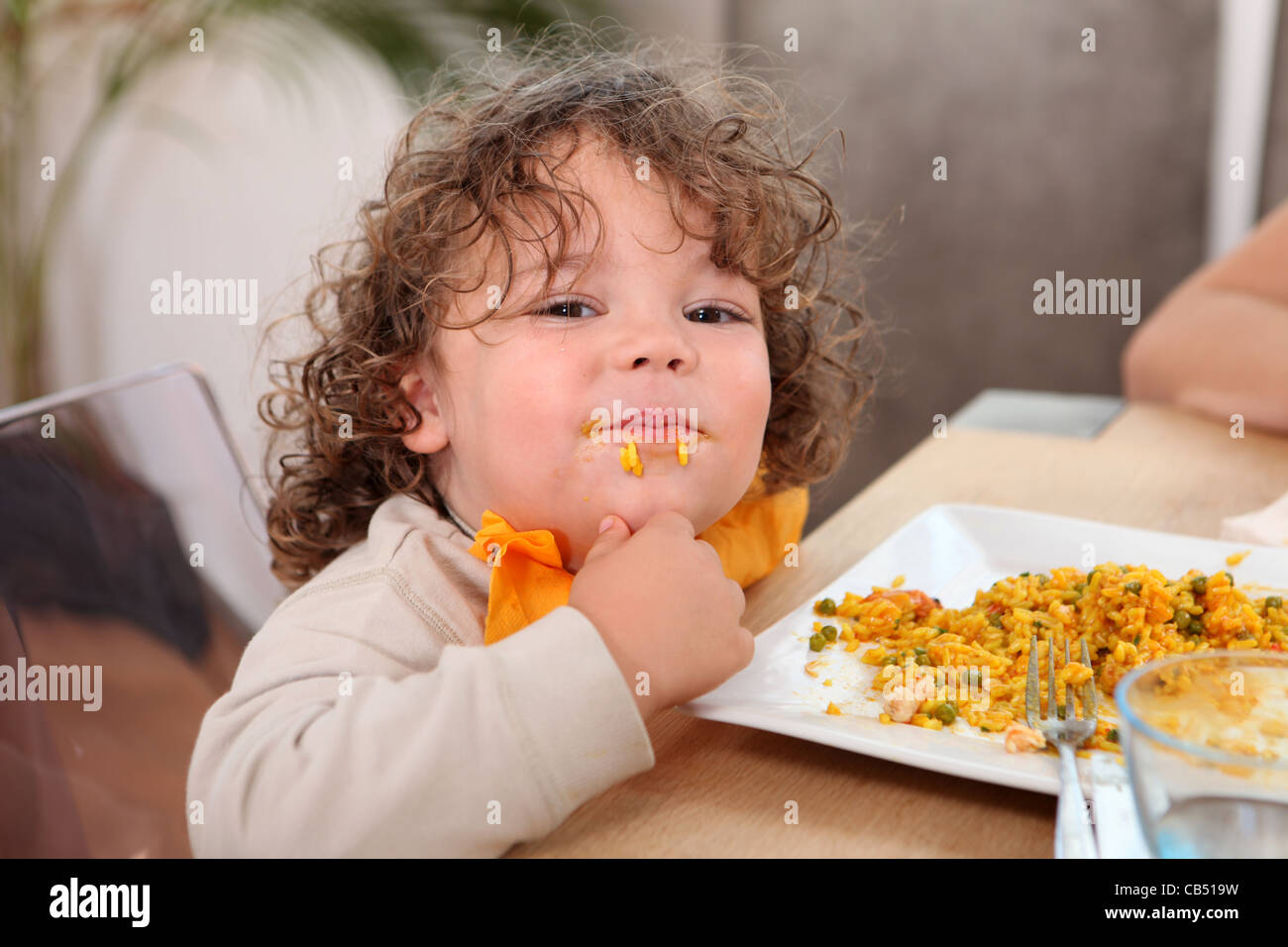 Little boy eating rice at kitchen table Stock Photo - Alamy
