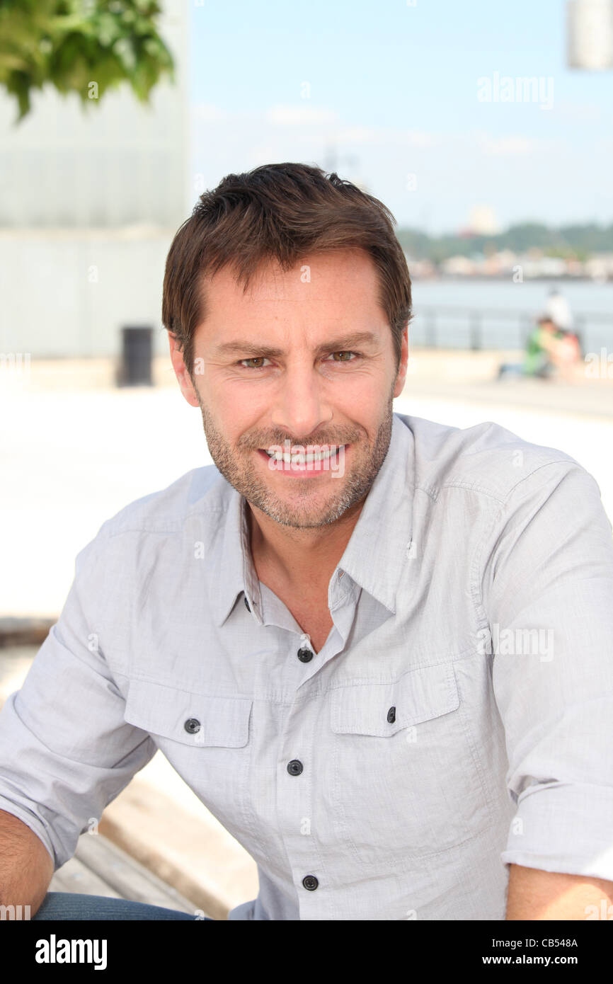 Man sat on bench water front in background Stock Photo - Alamy