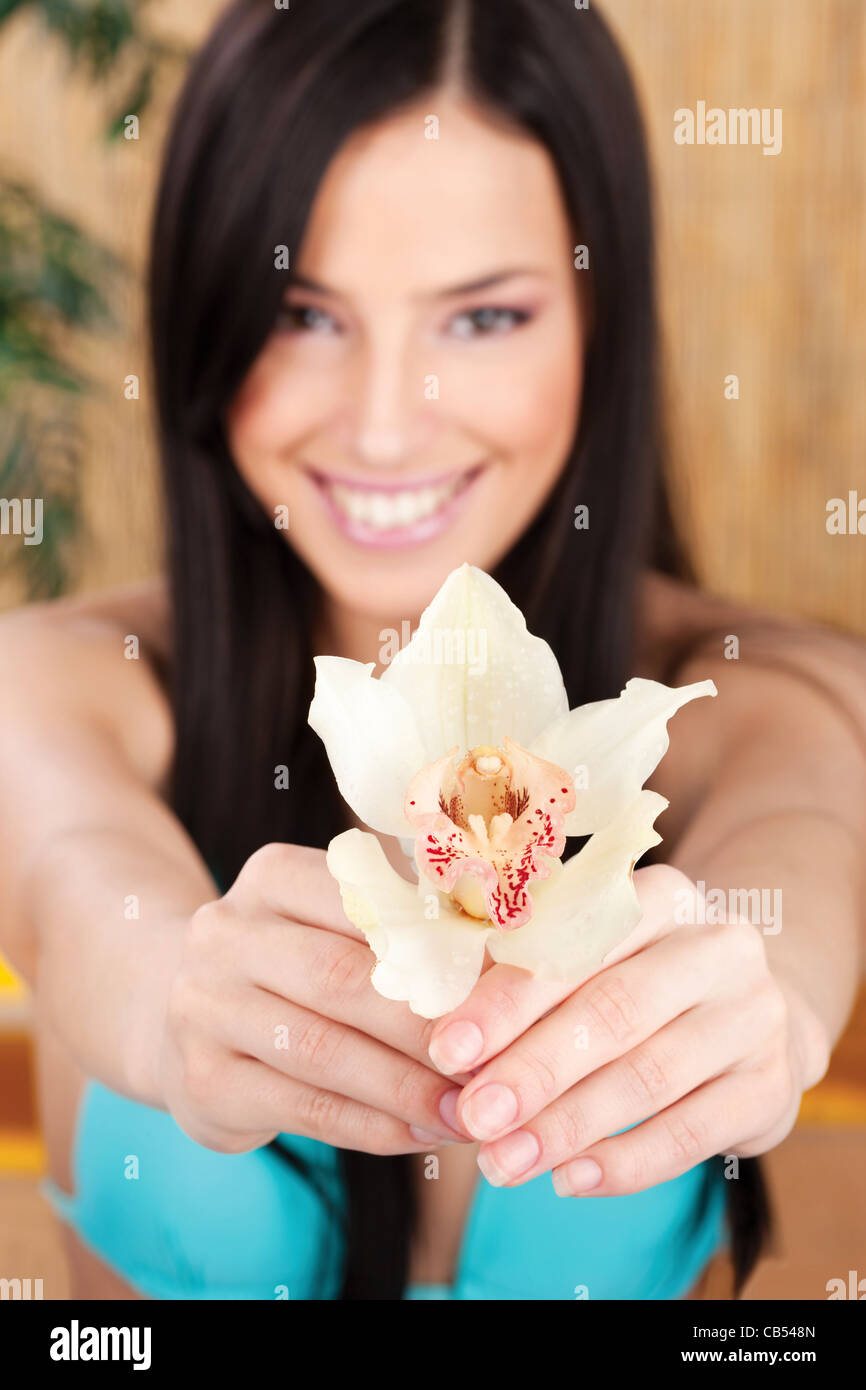 Pretty smiled woman holding white orchid in bikini, focus on flower ...