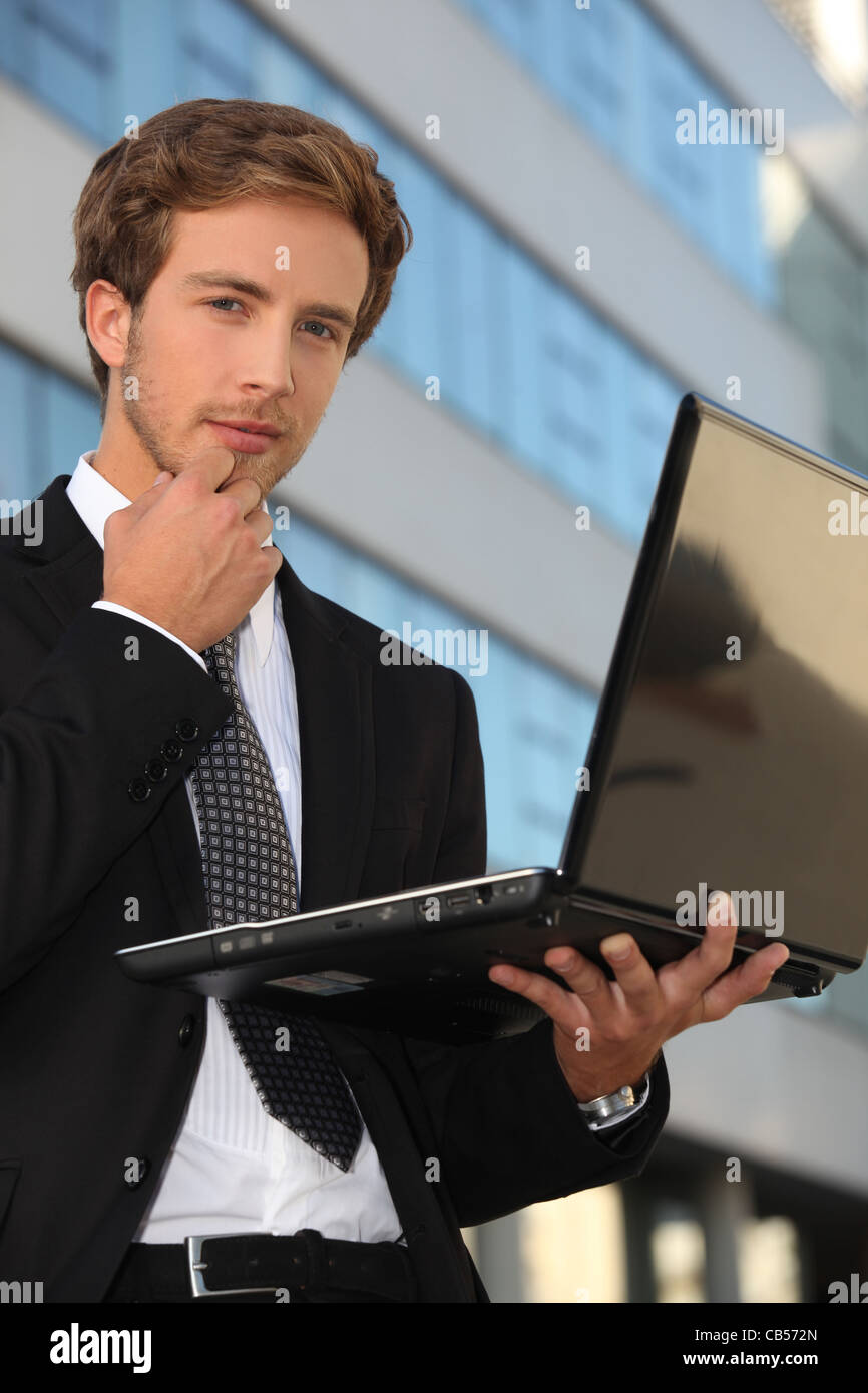 Smart man holding laptop standing outdoors Stock Photo - Alamy
