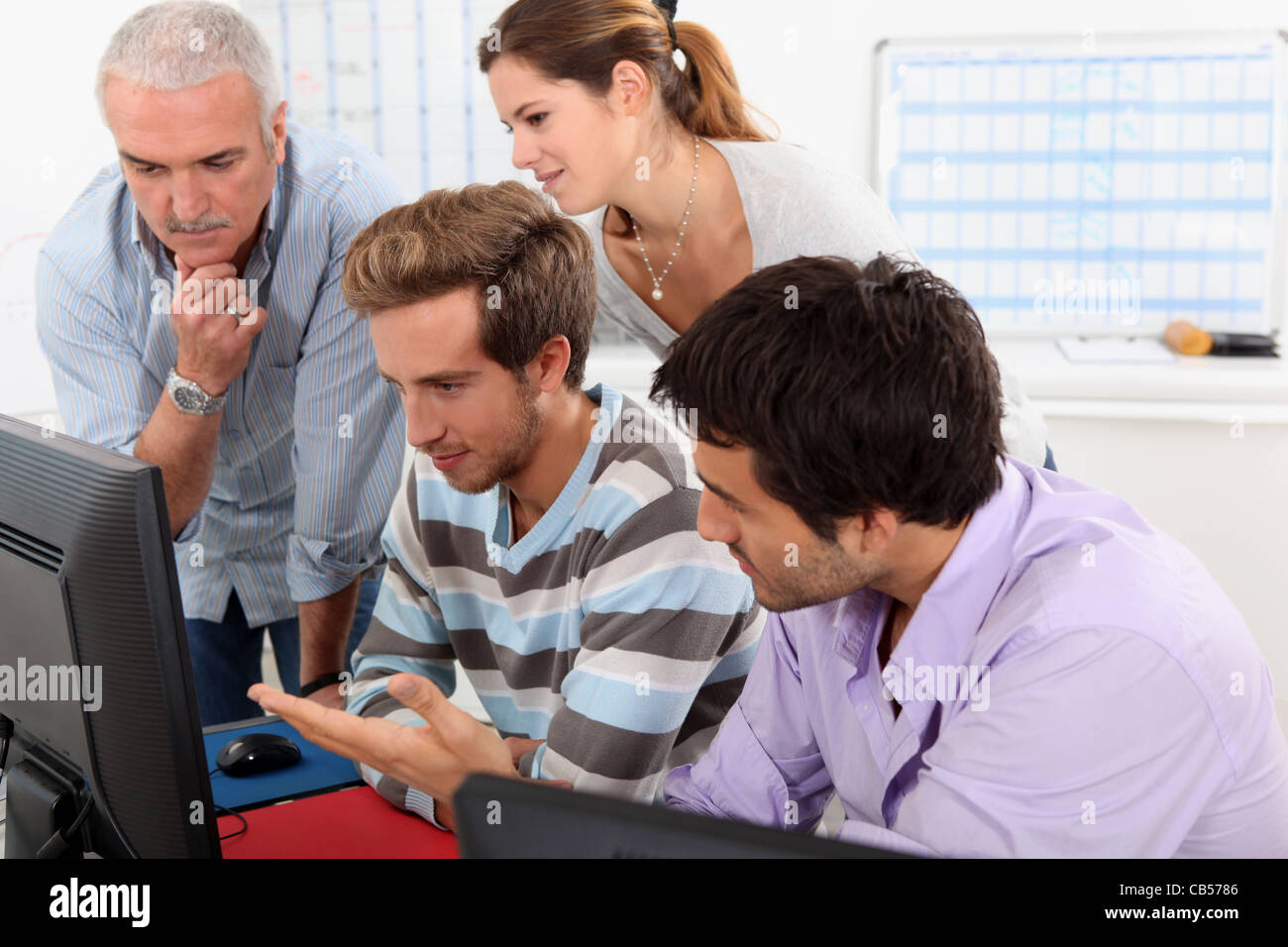 Group of people sitting round a computer Stock Photo - Alamy
