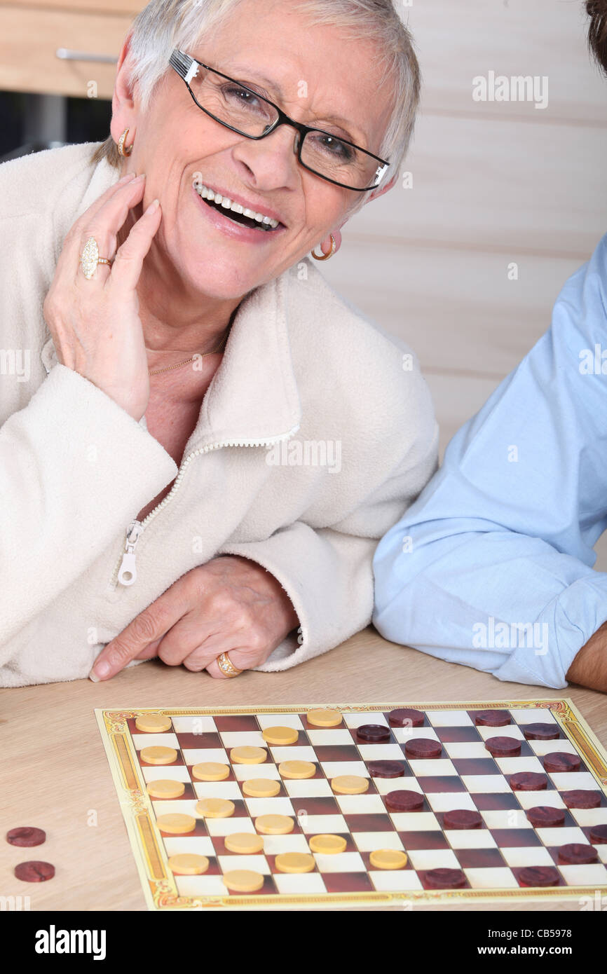 An old laughing lady playing checkers with somebody Stock Photo - Alamy