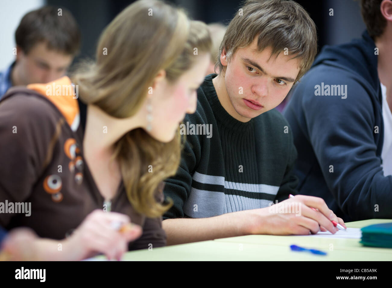 pretty female college student sitting in a classroom full of students ...
