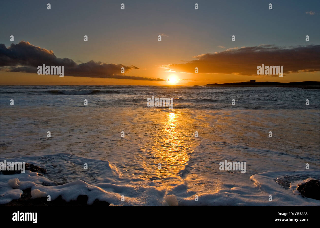 Orange sunset over waves on a beach Stock Photo - Alamy