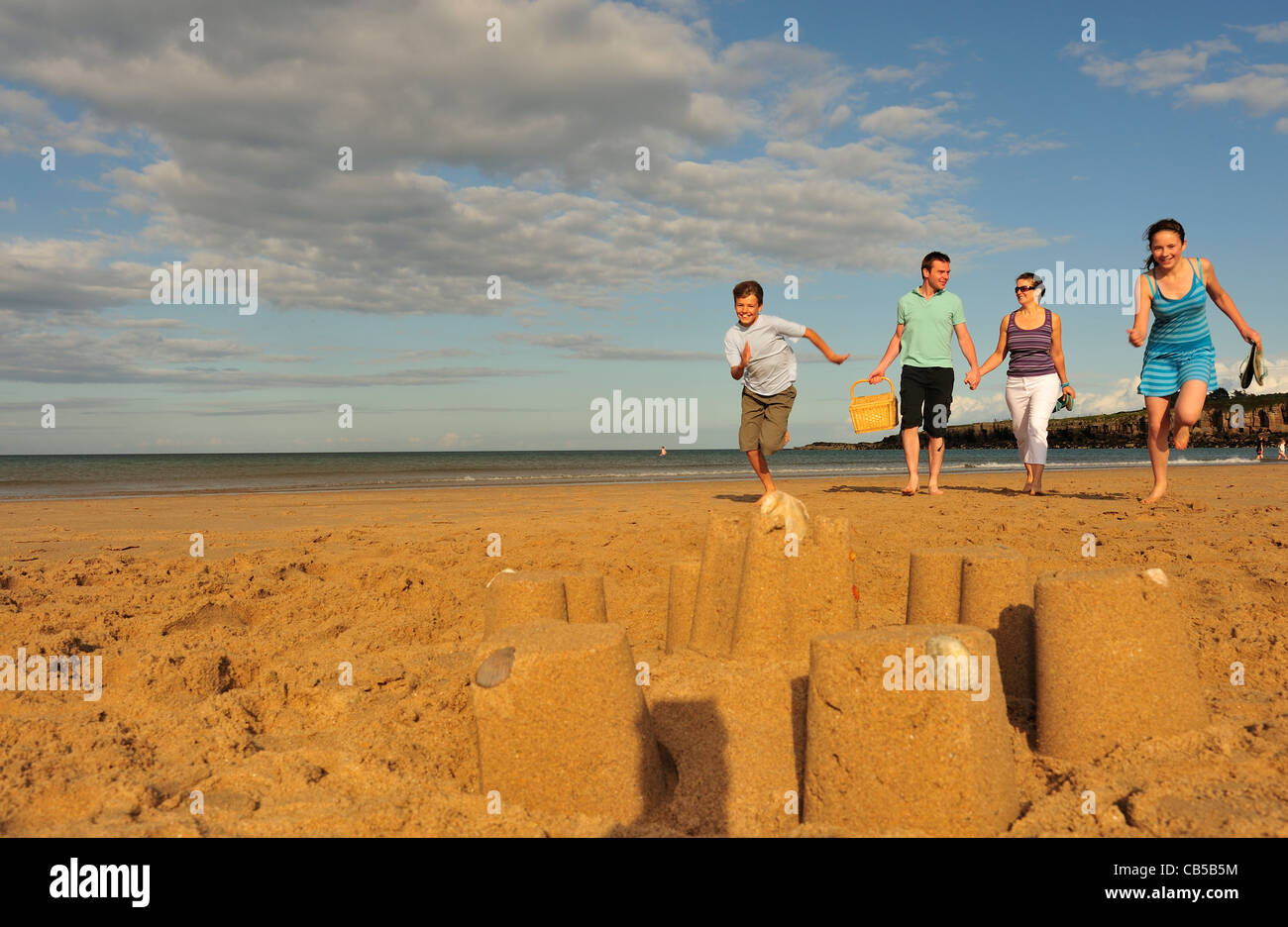 Family on sandy beach with sand castle Stock Photo - Alamy