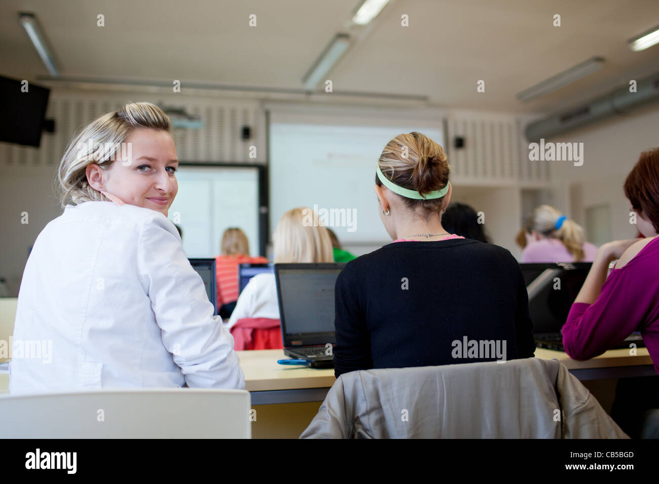 college students sitting in a classroom, using laptop computers during ...